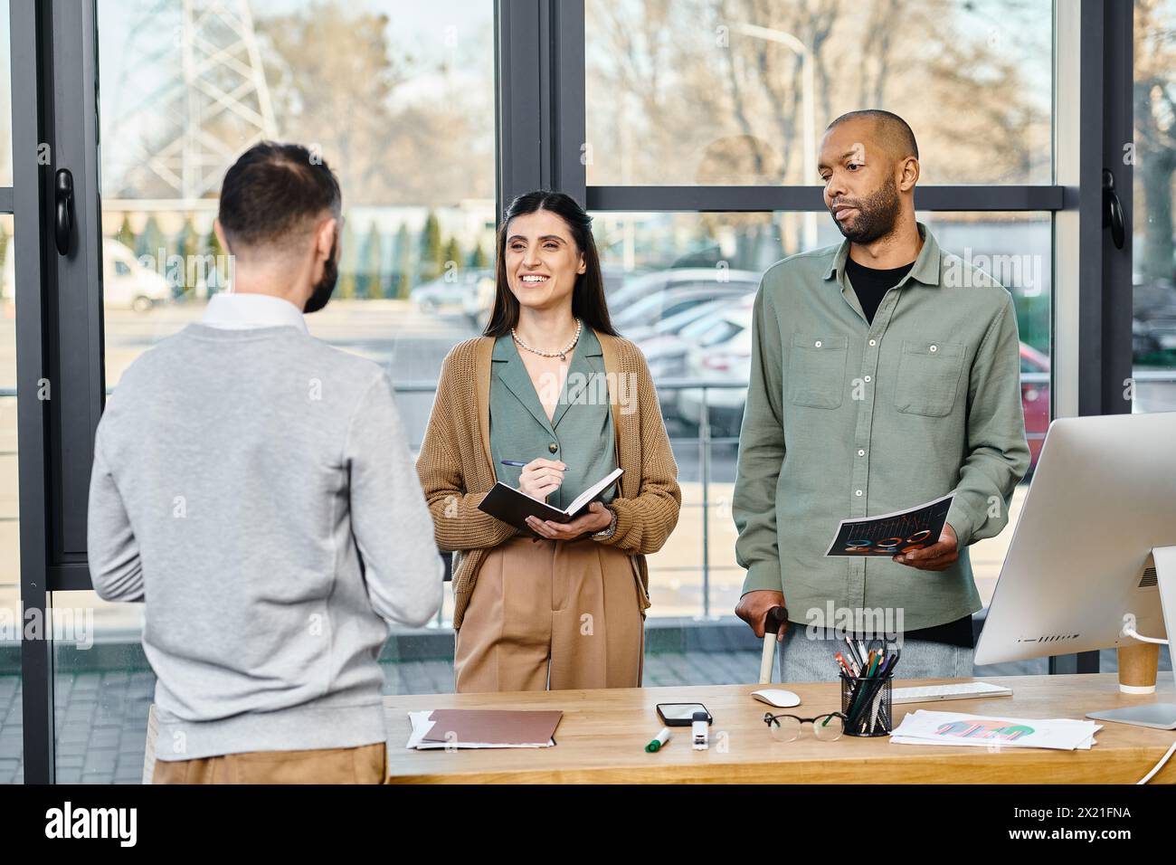 A diverse group of professionals gathered around a desk, engaged in discussing and brainstorming ...