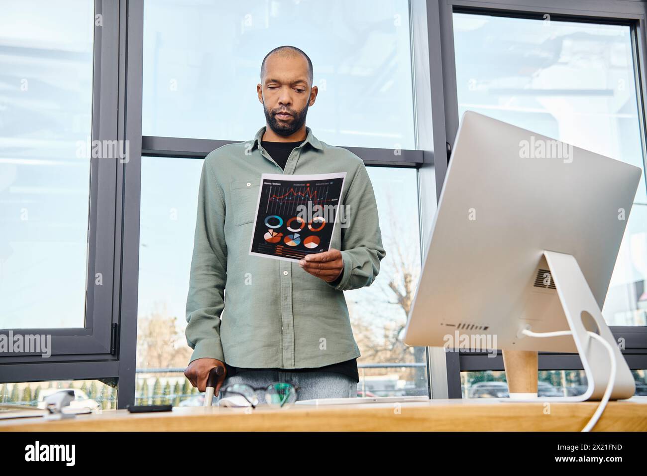 A man in an office standing before a large computer monitor, immersed ...