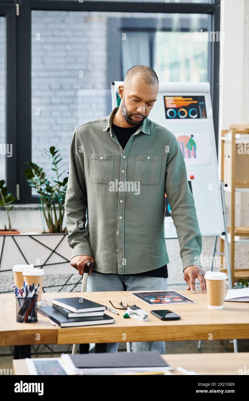 disabled man standing in front of a table, holding a cup of coffee in ...