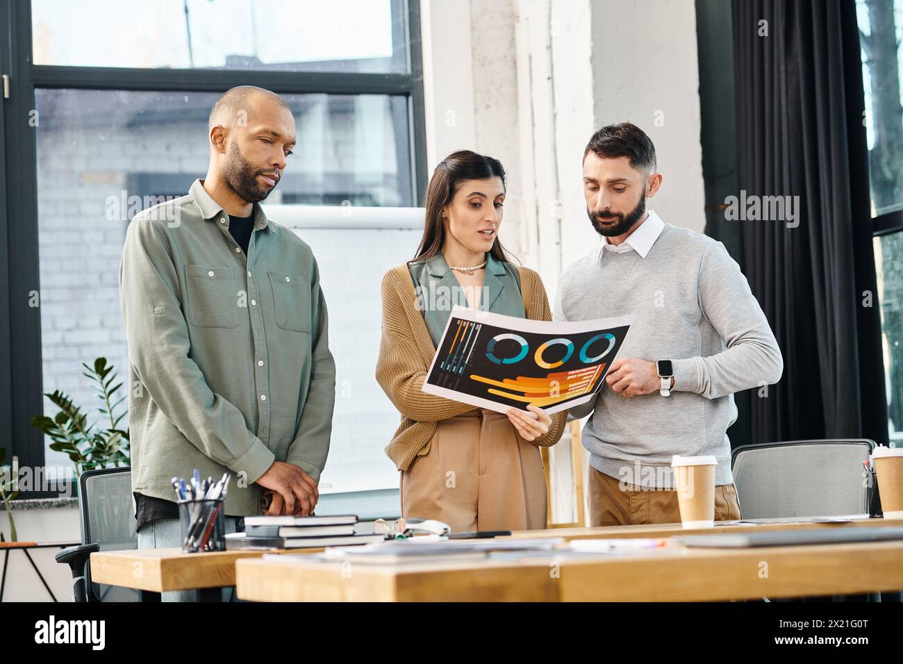 A diverse group of professionals stand around a table, engrossed in a ...