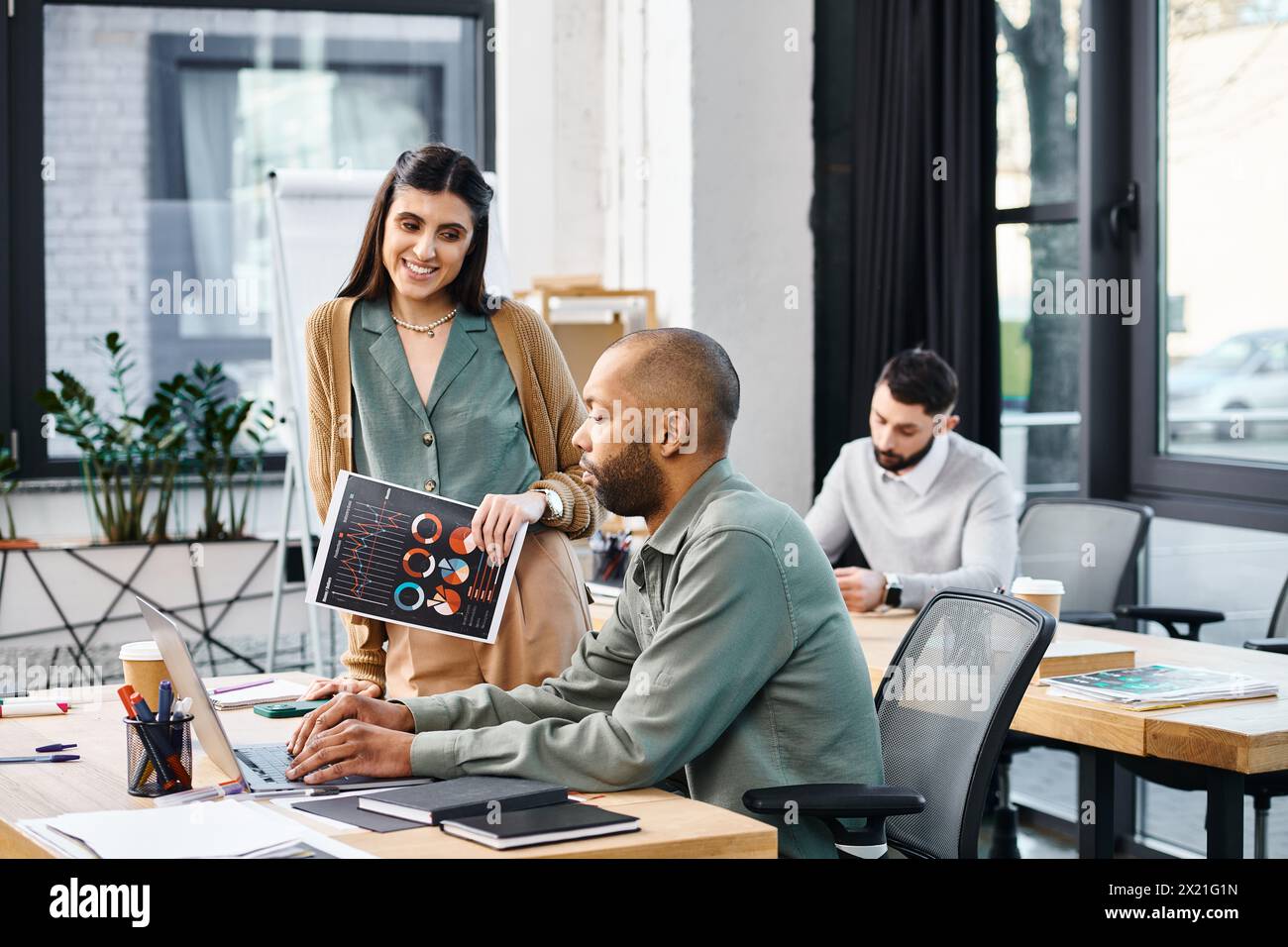 A man and woman engage in a focused discussion at a sleek office table ...