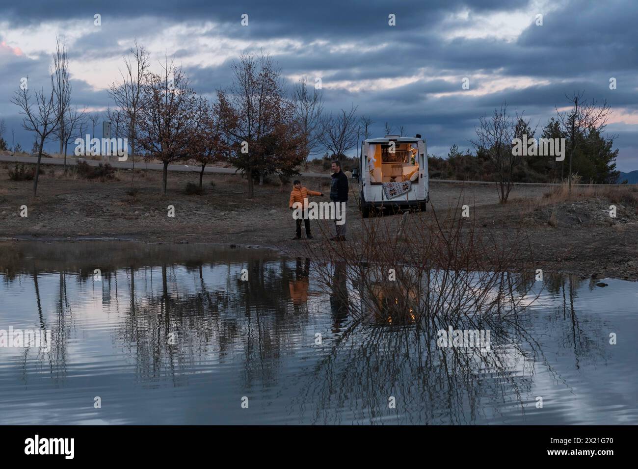 Father and son play throwing stones into the lake at sunset during ...