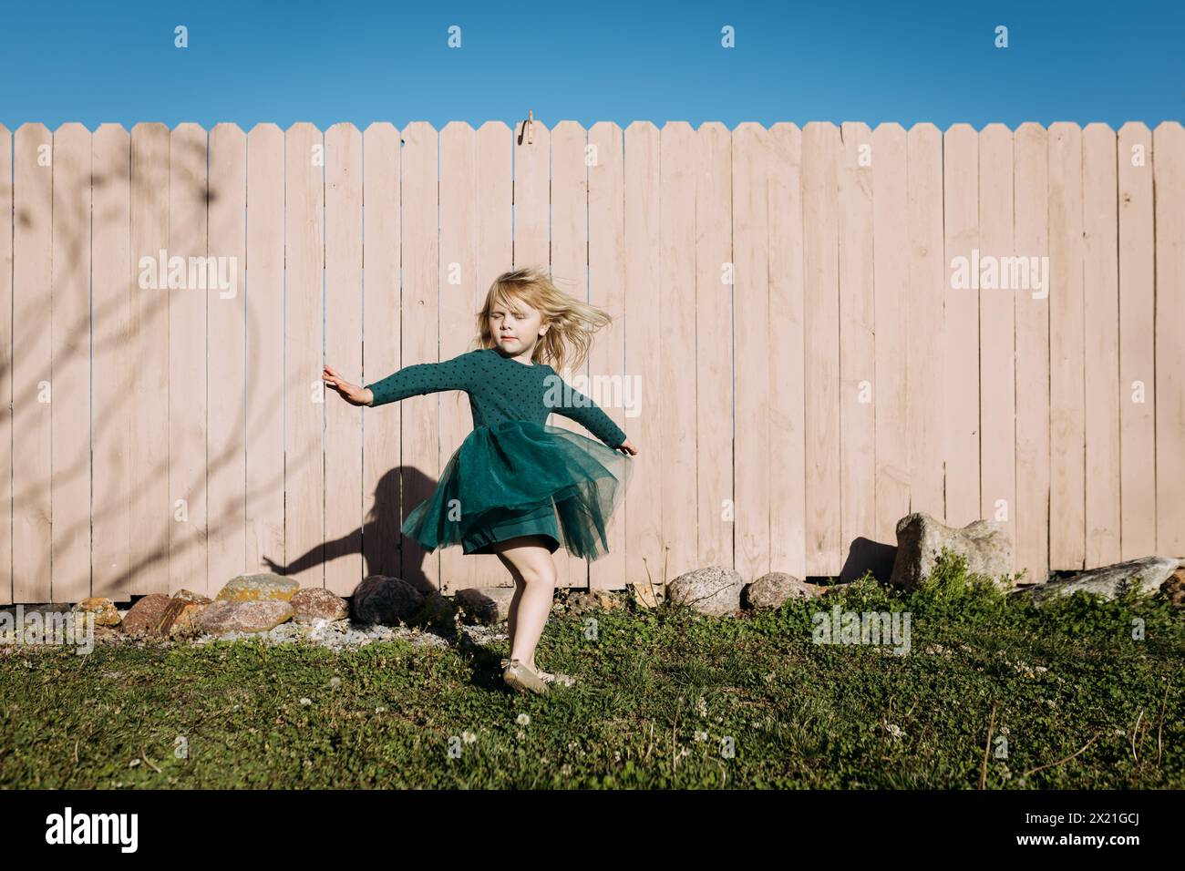 Carefree child twirling in yard against wooden fence Stock Photo - Alamy