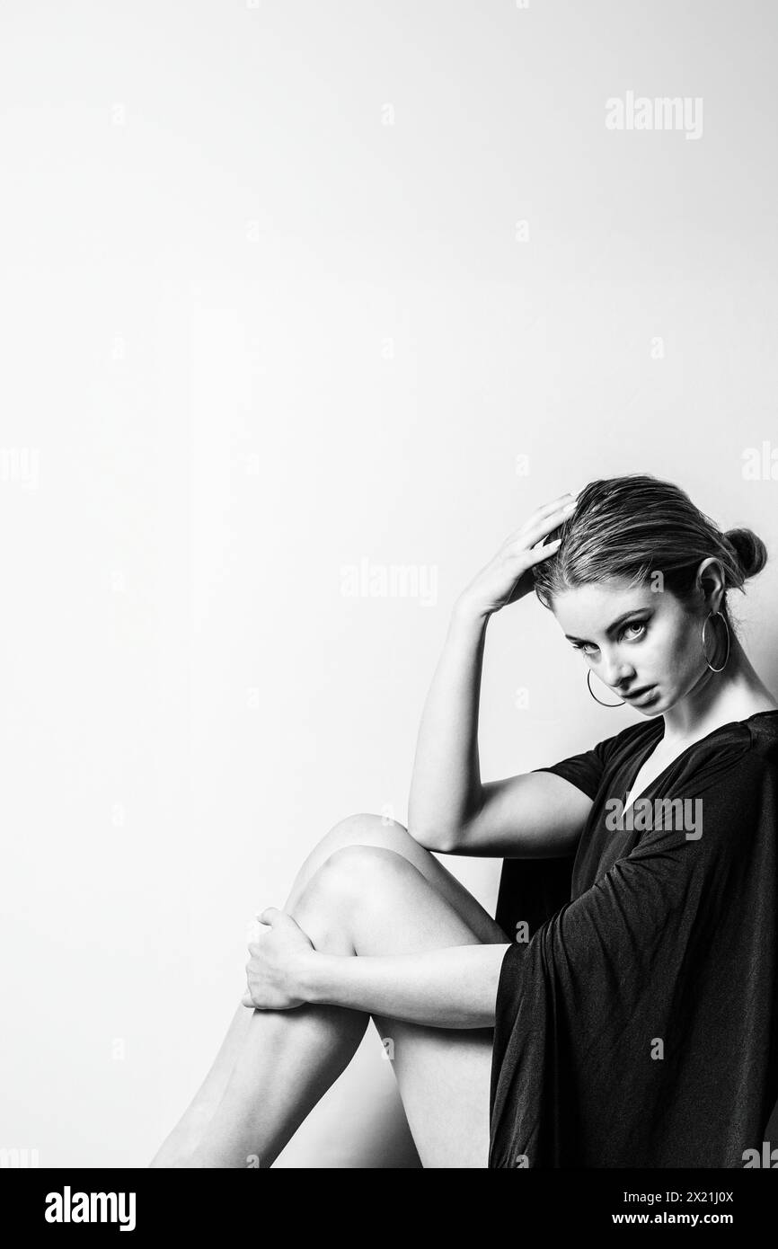 Monochromatic portrait of pensive lady sitting down looking at camera ...
