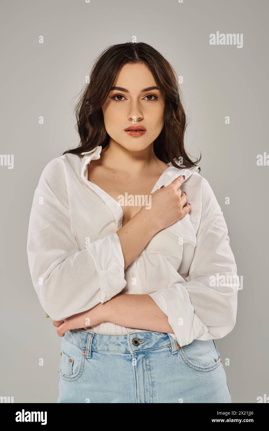 A stunning plus-size woman strikes a pose in a white shirt against a ...