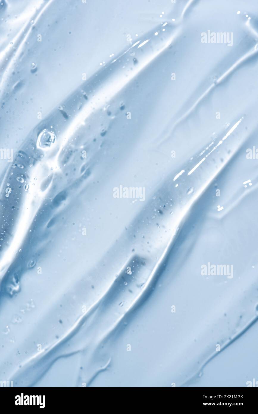 Clear cosmetic gel texture on blue close up. Acid face serum, sanitizer ...