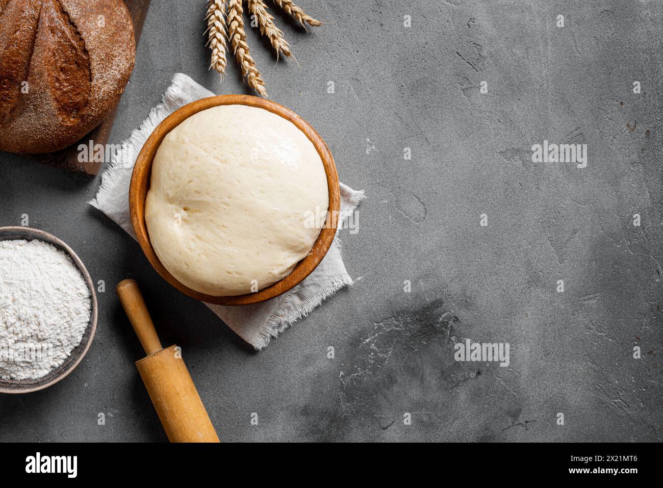 Bowl of fresh yeast dough on concrete table, top view, copy space. Raw dough with flour, rolling ...