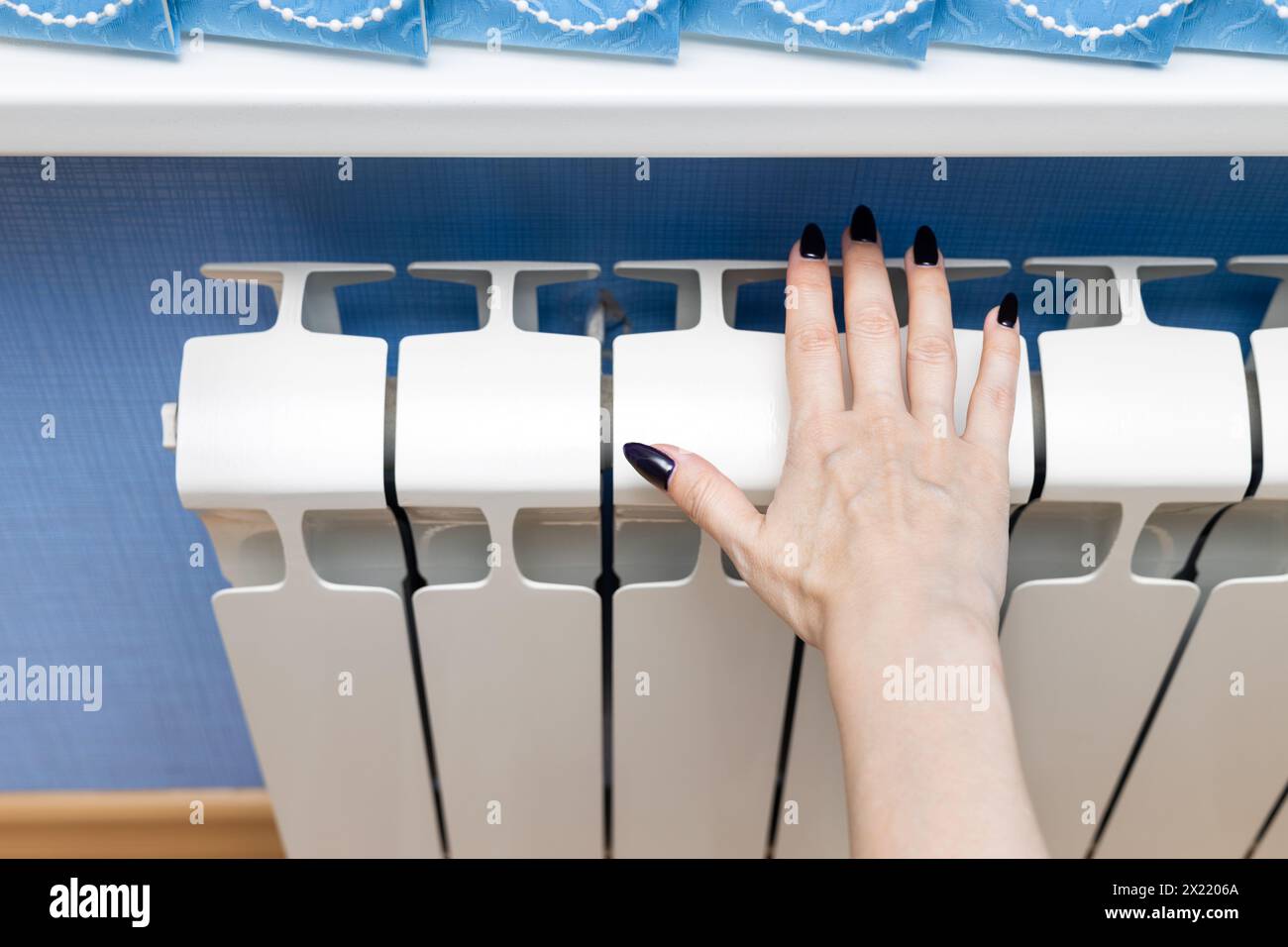 man checking the temperature of a heating radiator. a woman holds her ...