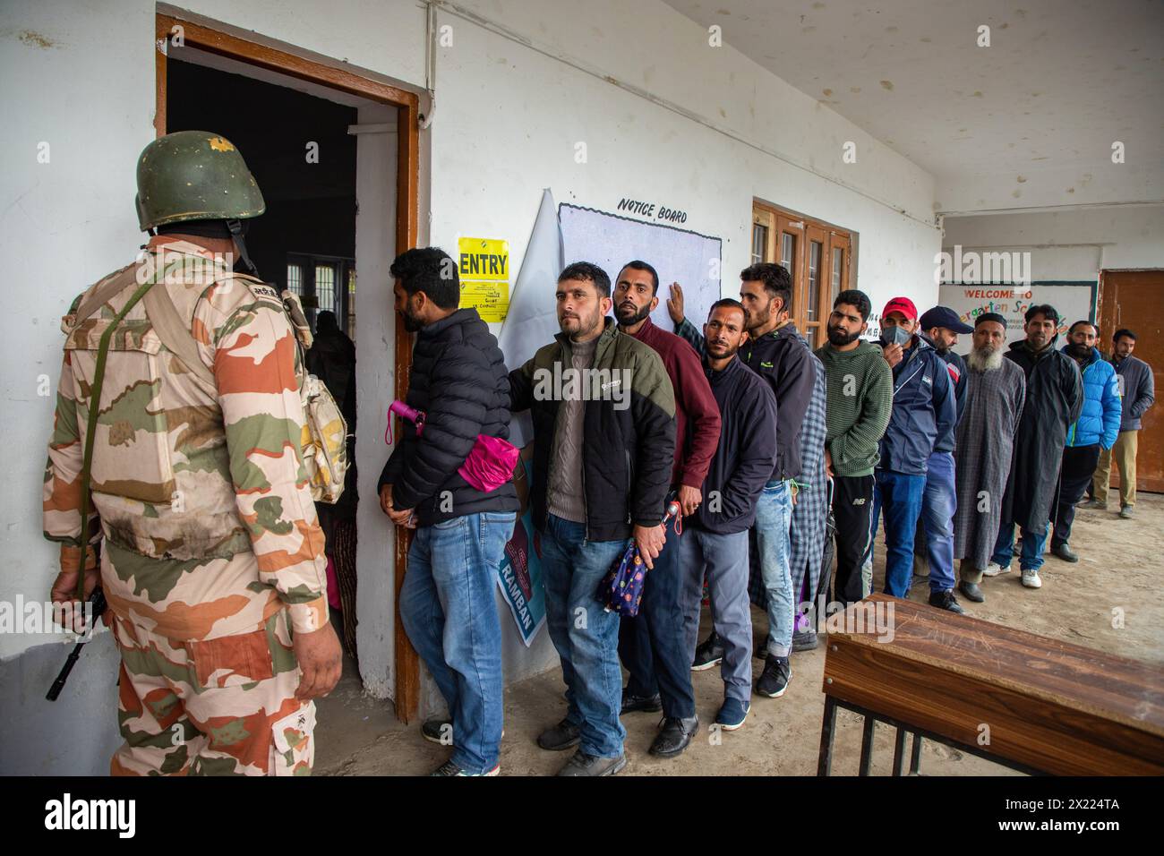 An Indian paramilitary soldier stands on guard as people wait in a ...