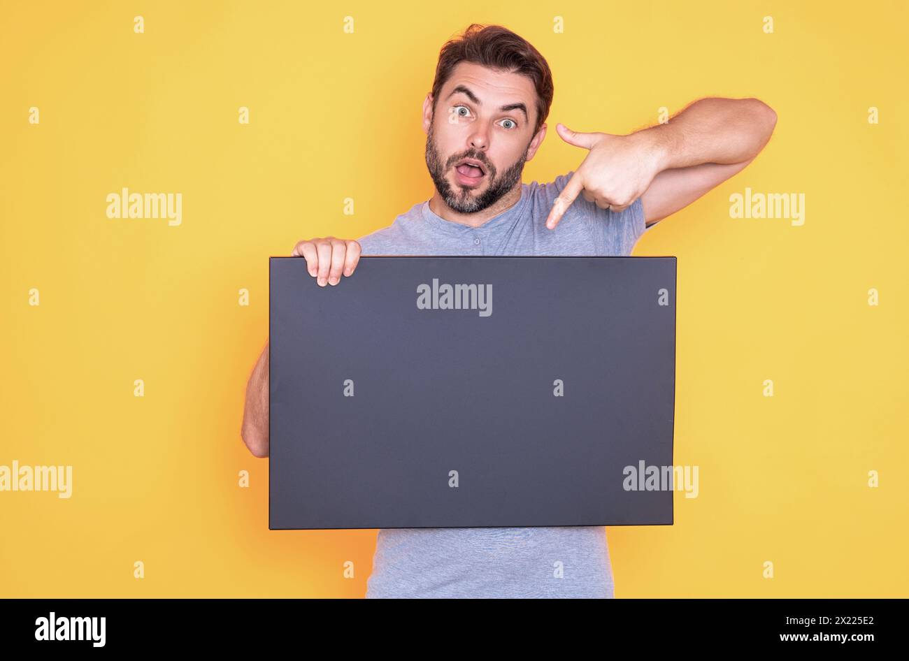 Man showing promo holding pointing finger on blank board on studio ...