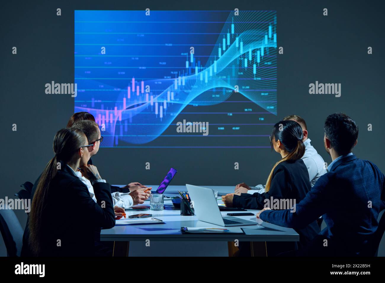 Office employees gather in boardroom, analyzing digital stock chart ...