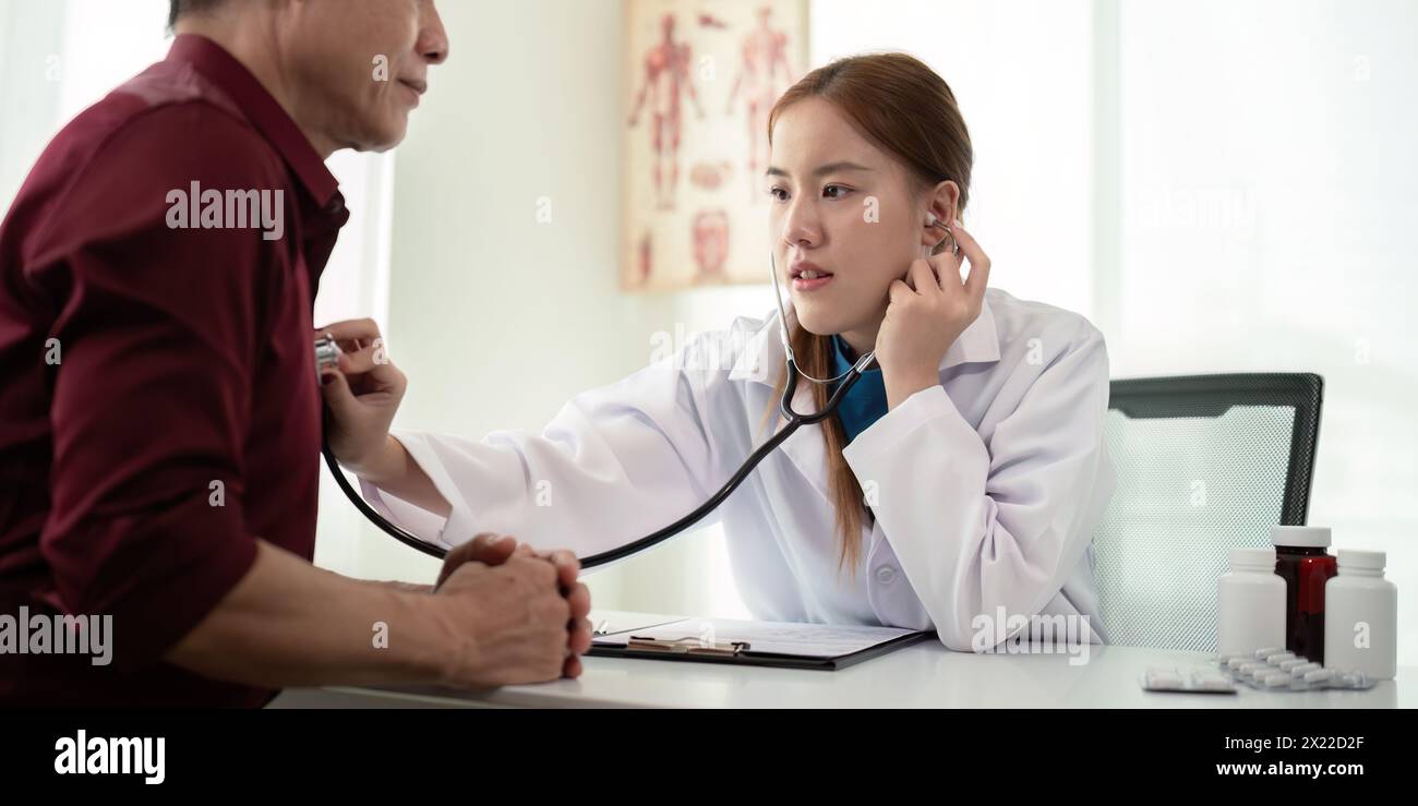 Female doctor asian cardiologist examining senior male cardiac patient ...