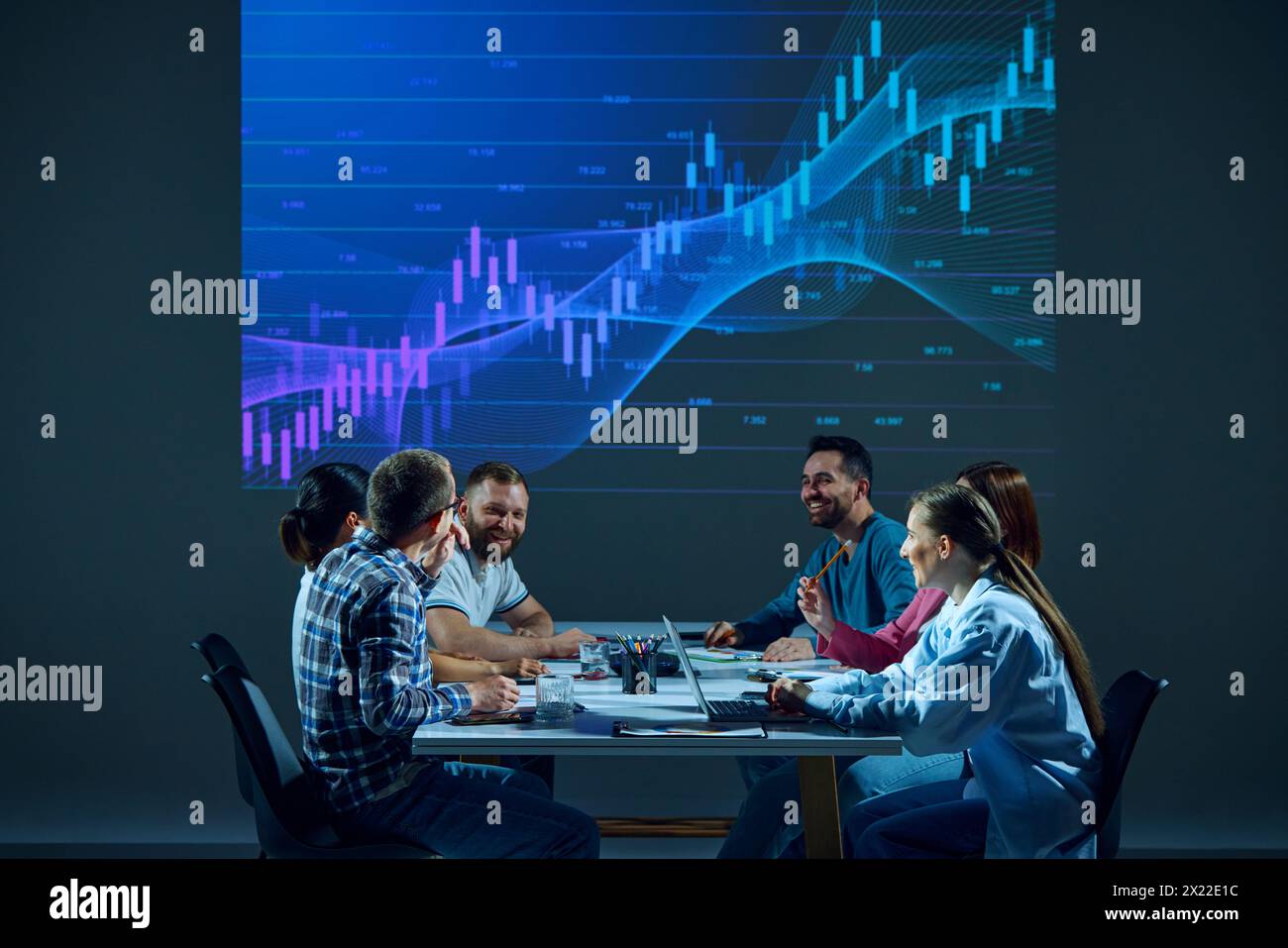 Teammates in a corporate environment sit around a conference table ...