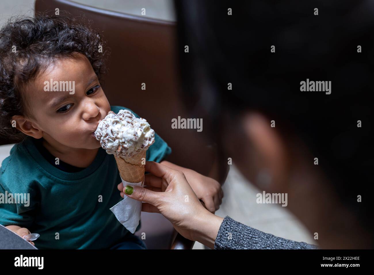 Mom And Her Latin American Son In A Shopping Mall Share An Ice Cream