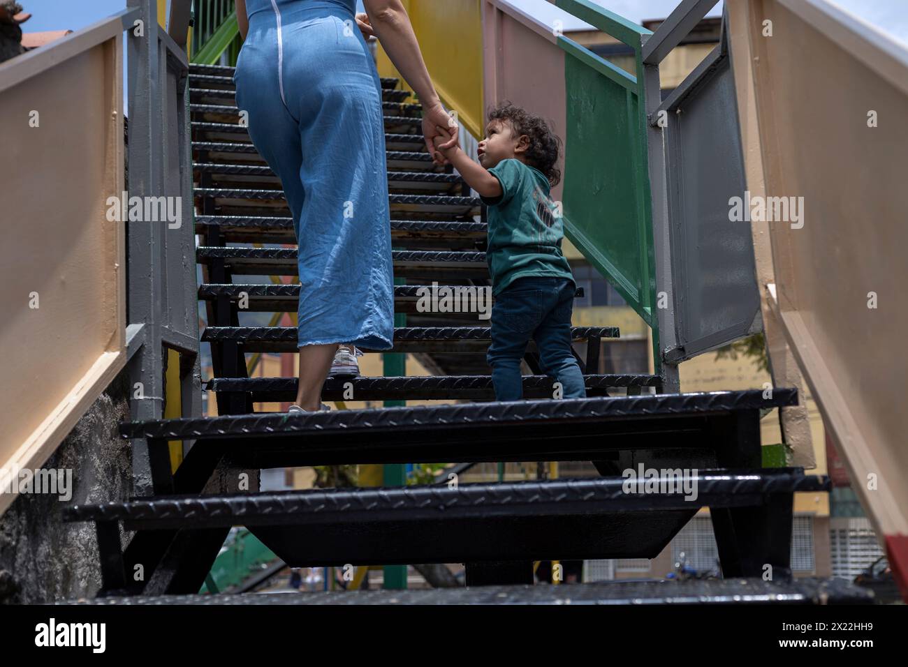 Latin American mom and son walk hand in hand up a flight of stairs on ...