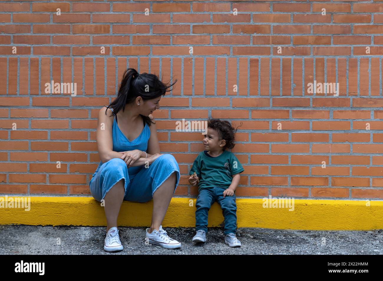 Latin American Mom chats with her son while they sit down to rest ...