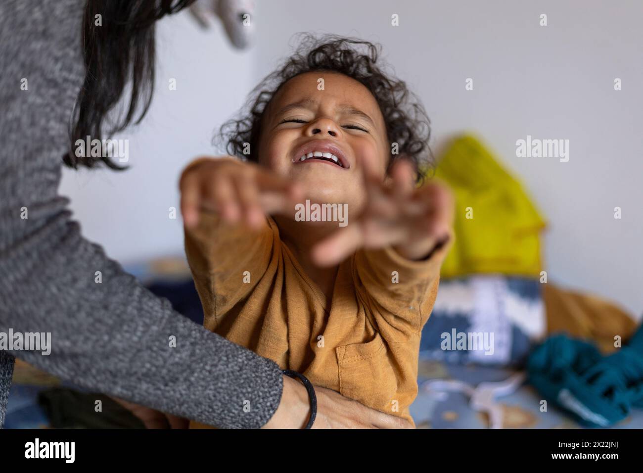Latin American boy (2) is upset because his mother is changing his ...
