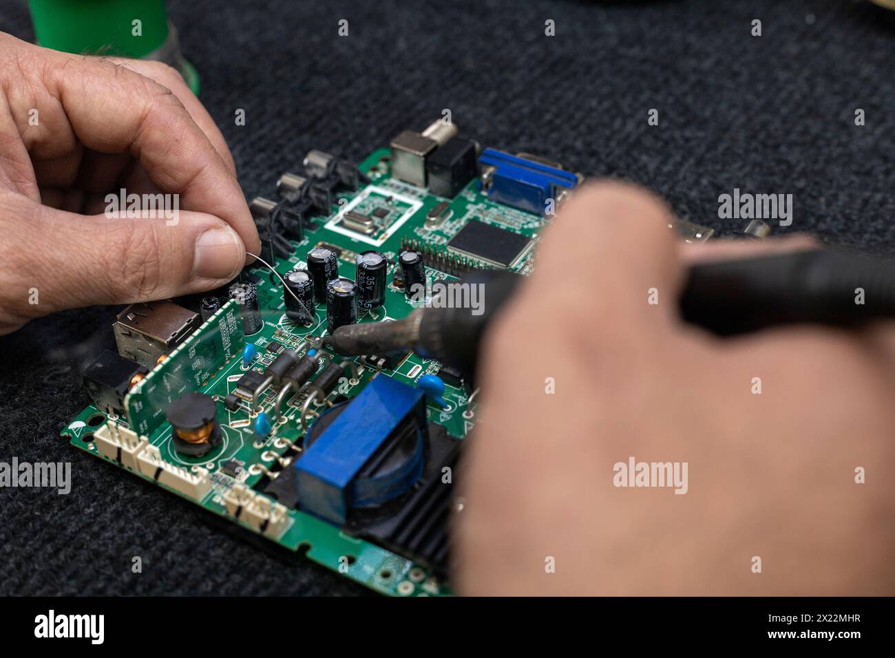 Electronic circuit board being repaired with soldering iron and tin ...