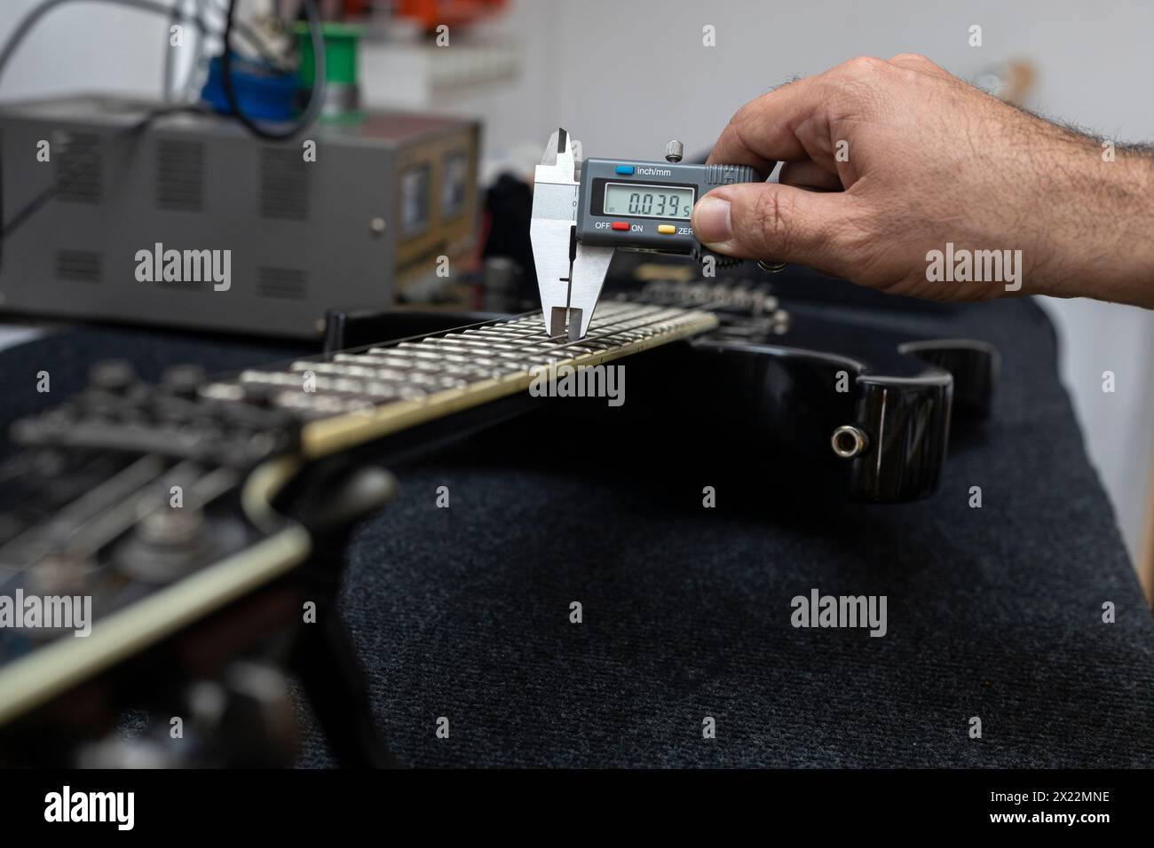 Latin American luthier calibrates the strings of an electric guitar ...