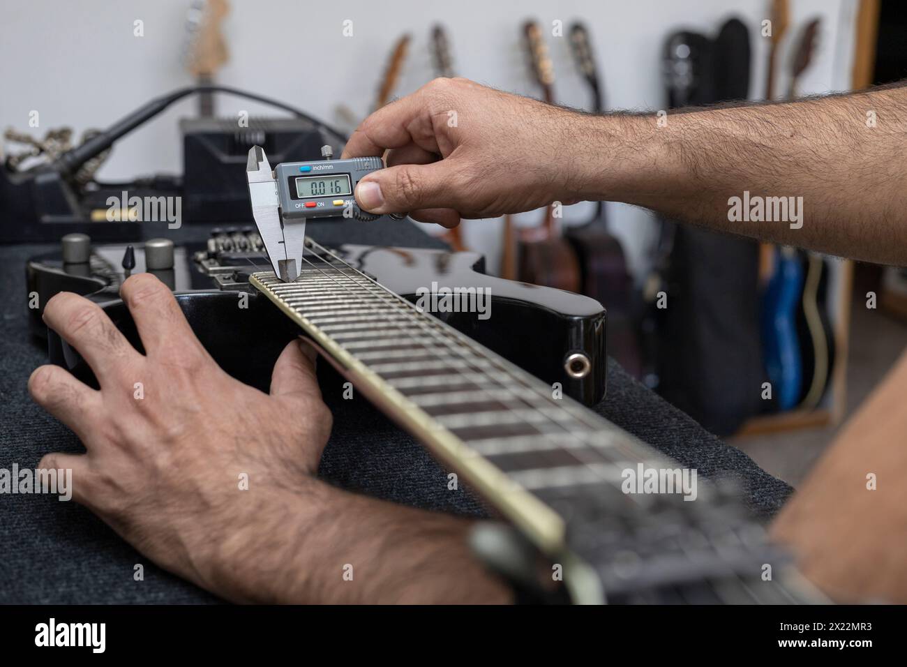 Latin American luthier calibrates the strings of an electric guitar ...