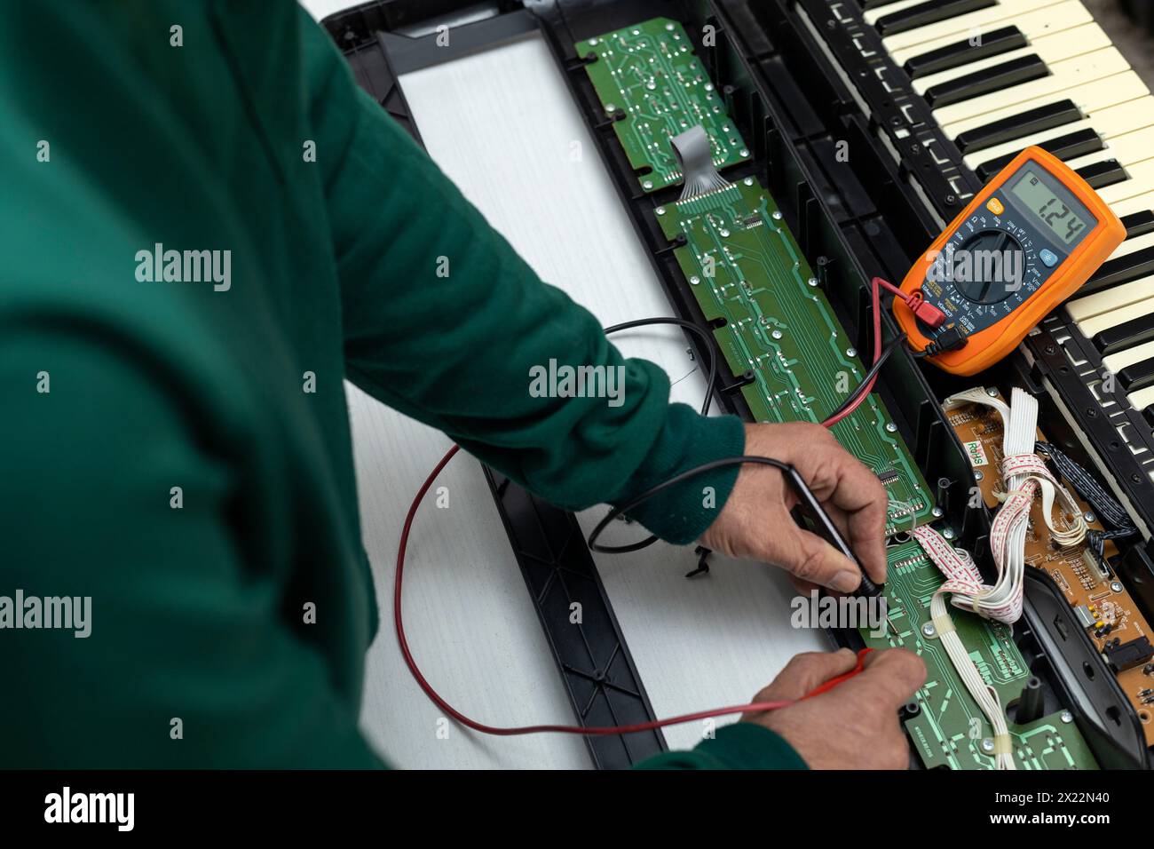Hands of Latin American electronic technician with a multimeter makes ...
