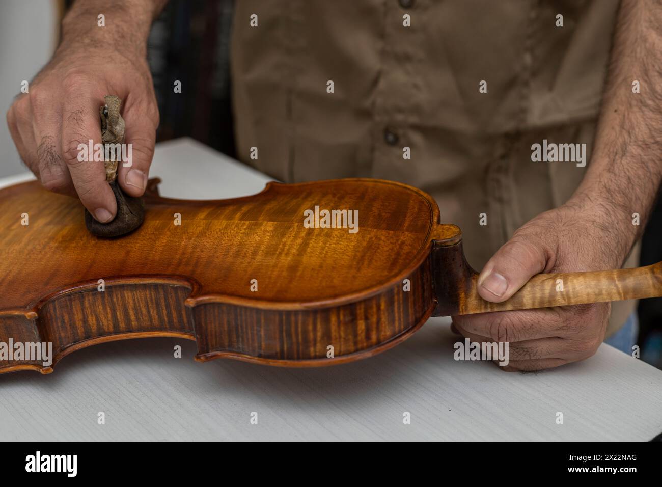 Close-up of unrecognizable Latin American Luthier varnishes a violin ...