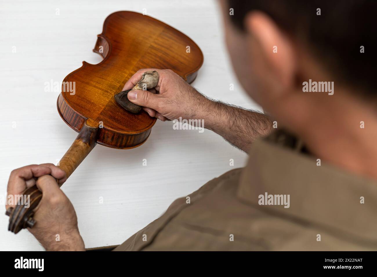 Close-up of unrecognizable Latin American Luthier varnishes a violin ...