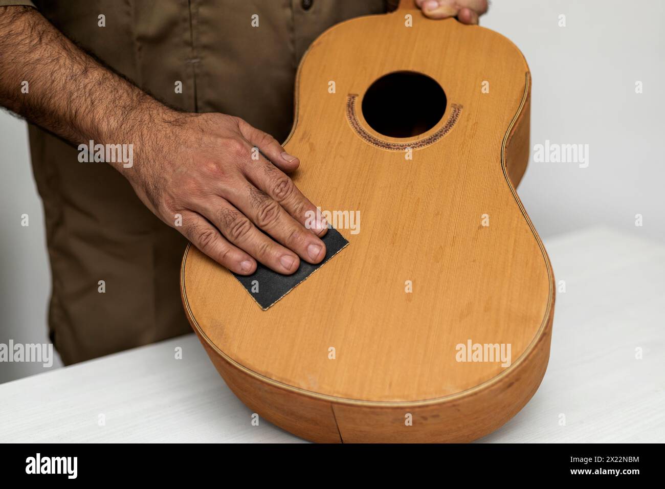 Luthier sands the front cover of a cuatro, instrument under ...
