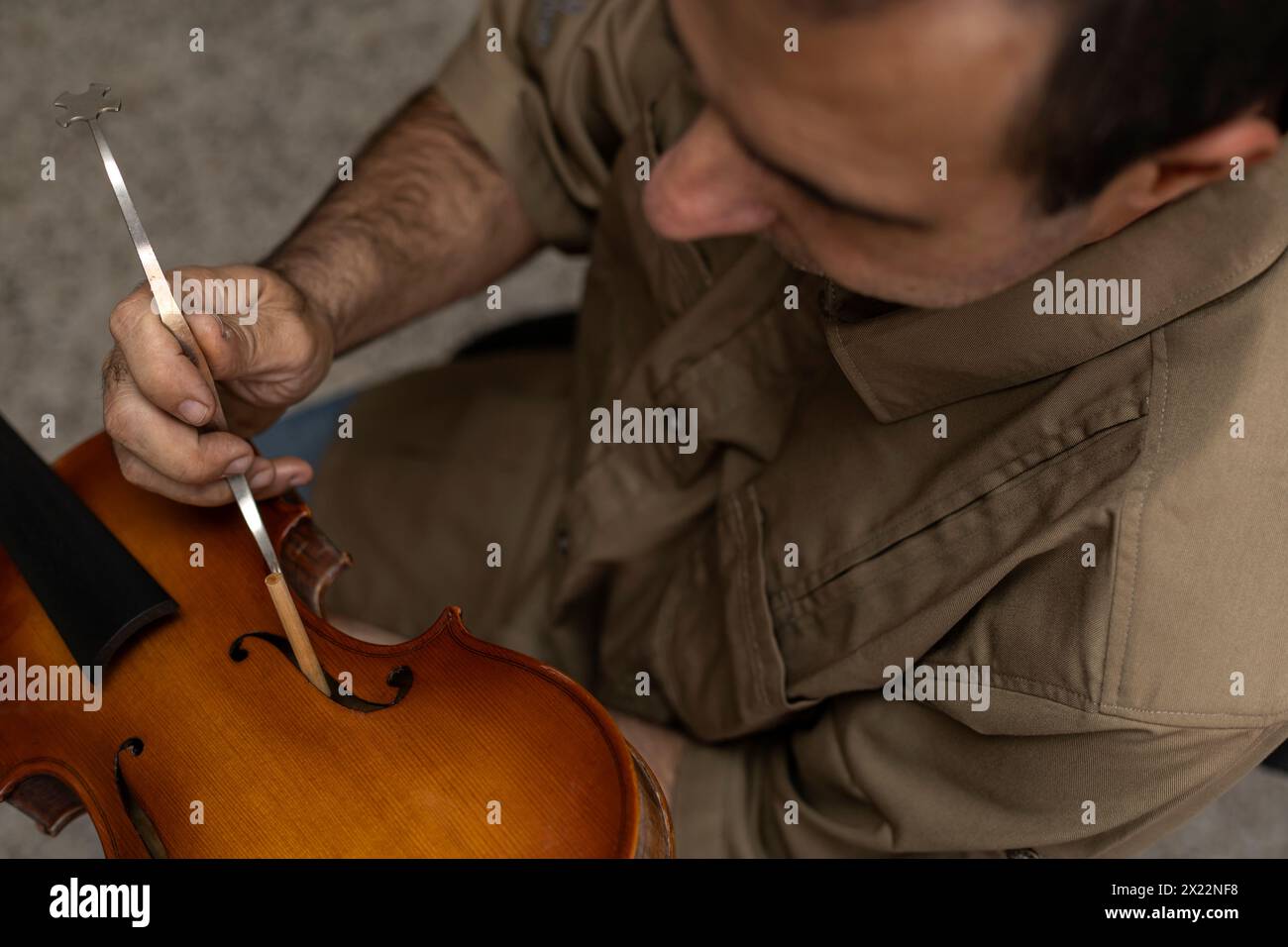 Latin American luthier placing a sound post between the top and the ...