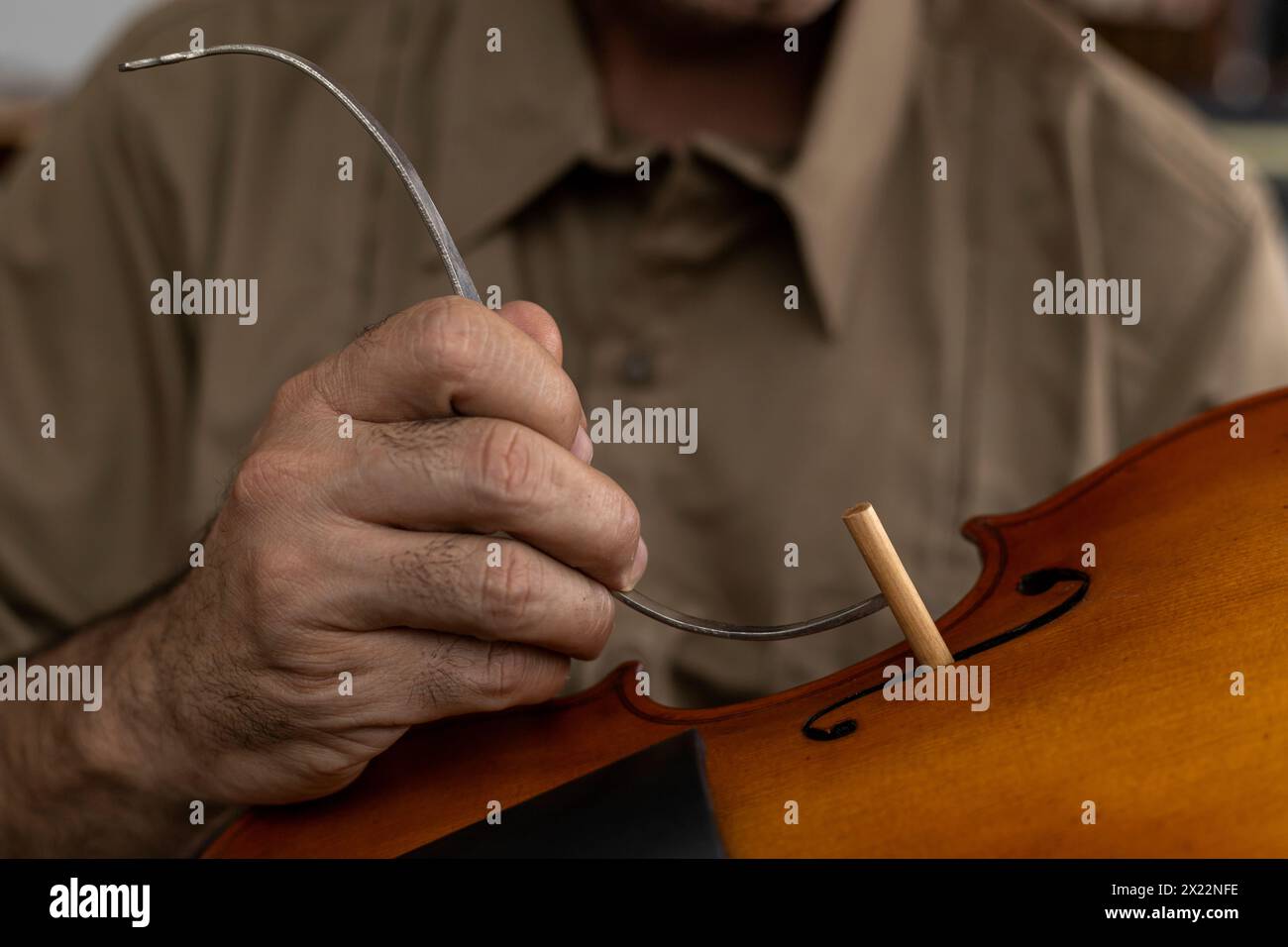 Latin American luthier placing a sound post between the top and the ...