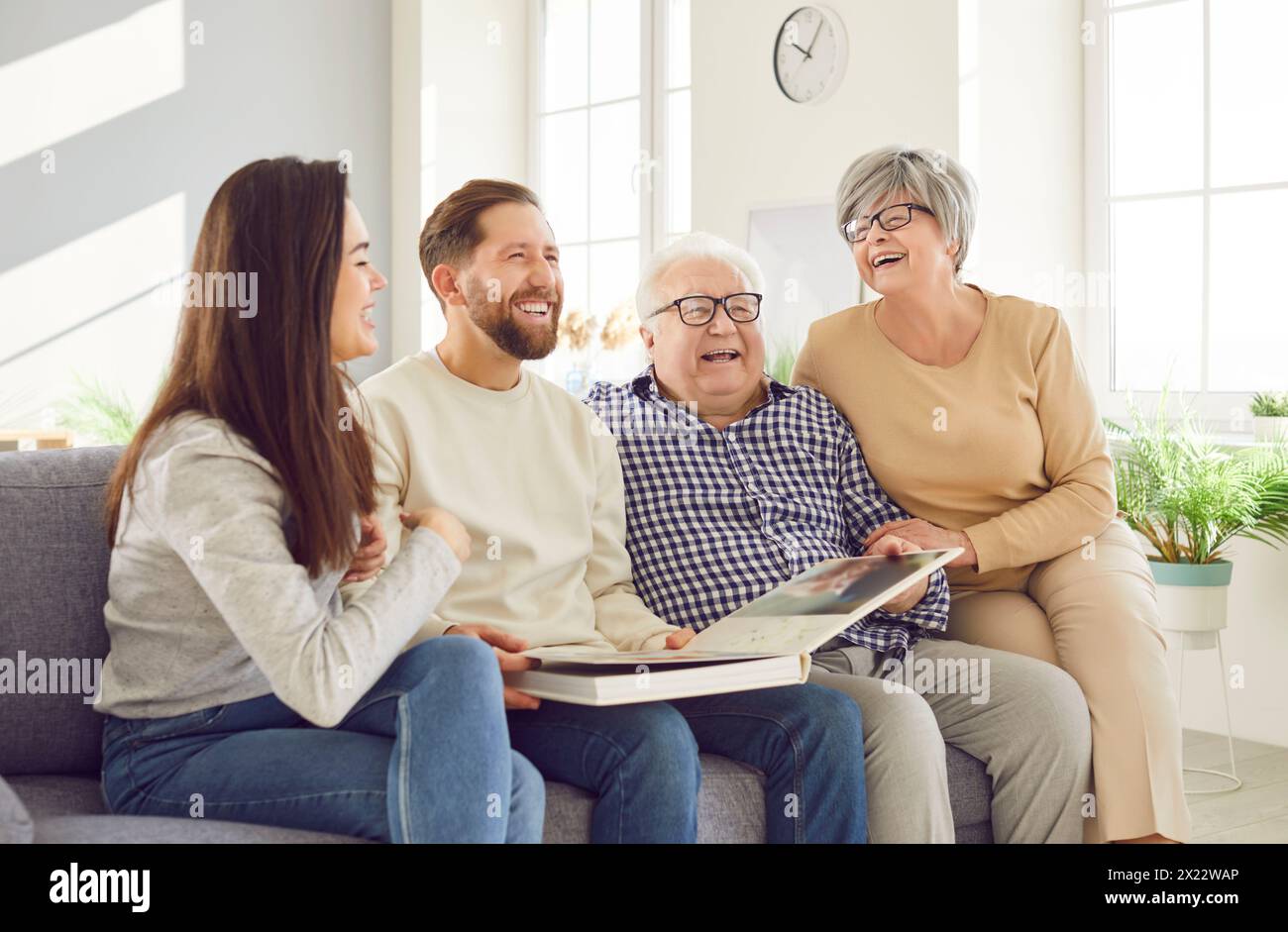Happy family, aging old parents and adult children watching photo album ...