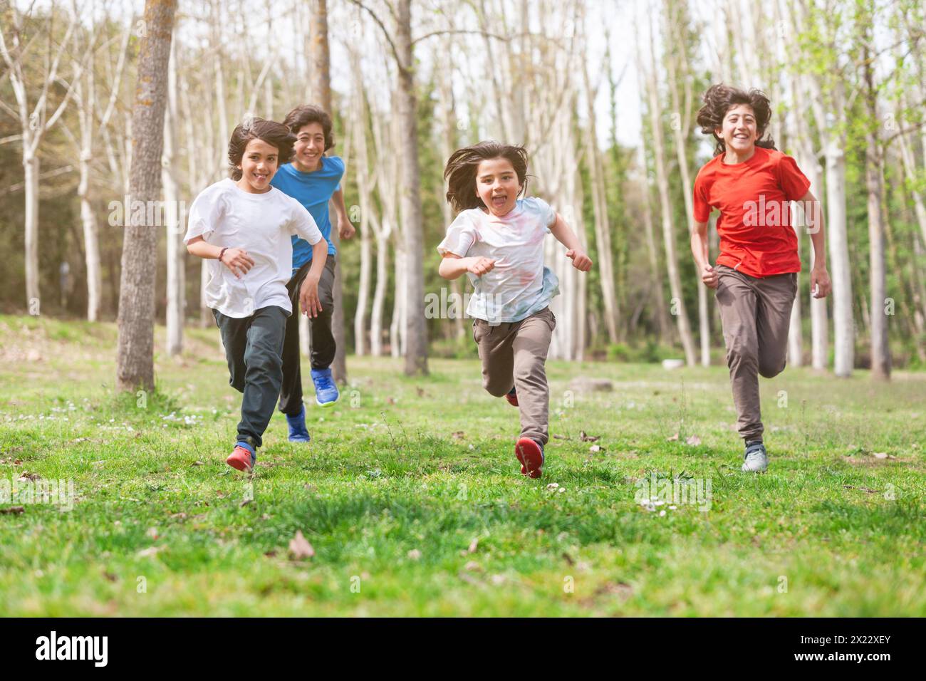Siblings of different ages running towards the camera through a meadow ...
