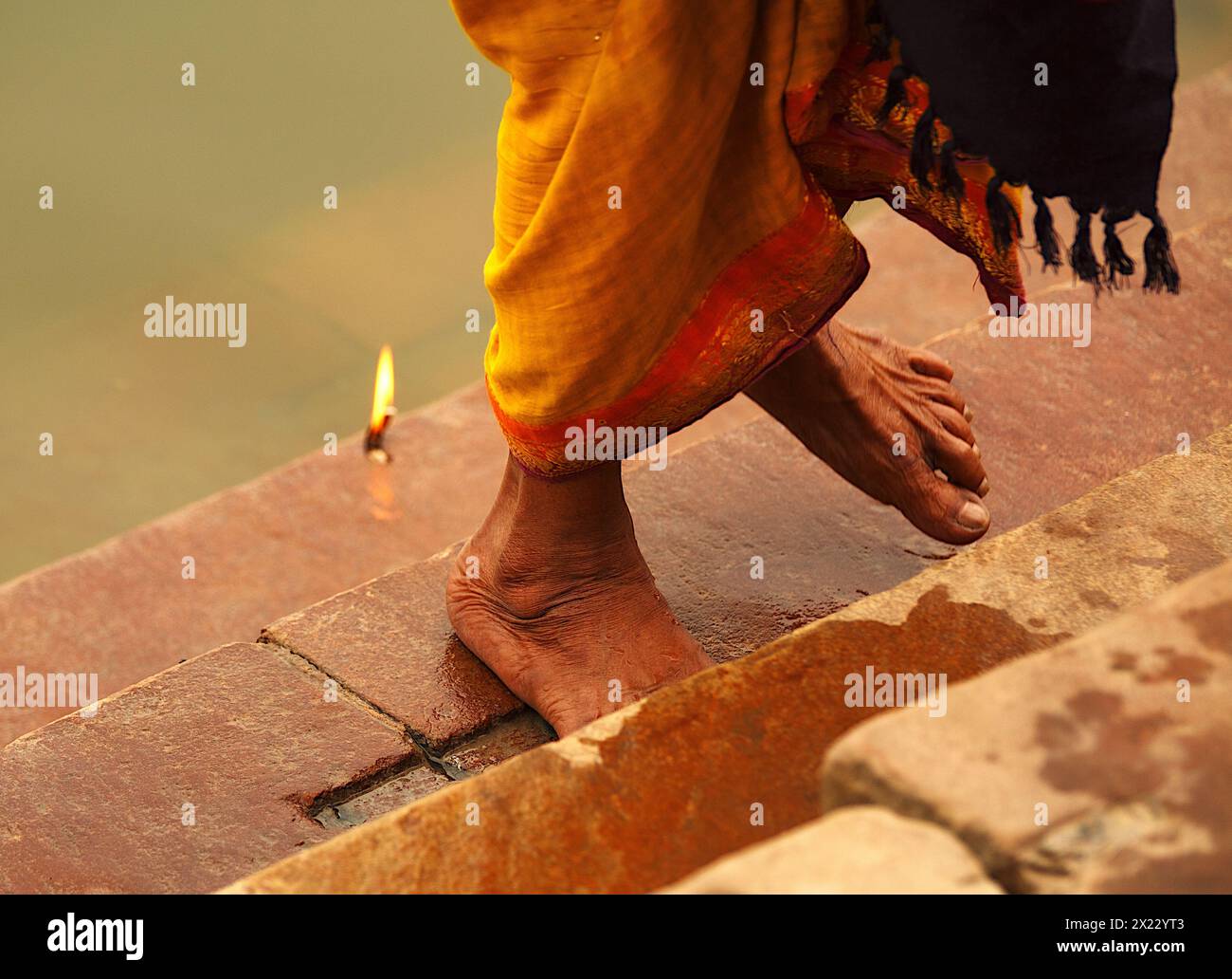 Feet of a pilgrim woman climbing the steps of a ghat by the Ganges ...