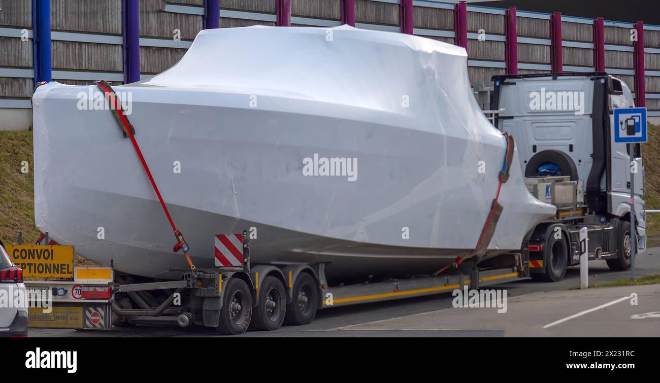 Heavy goods vehicle loaded with a yacht in a motorway car park ...