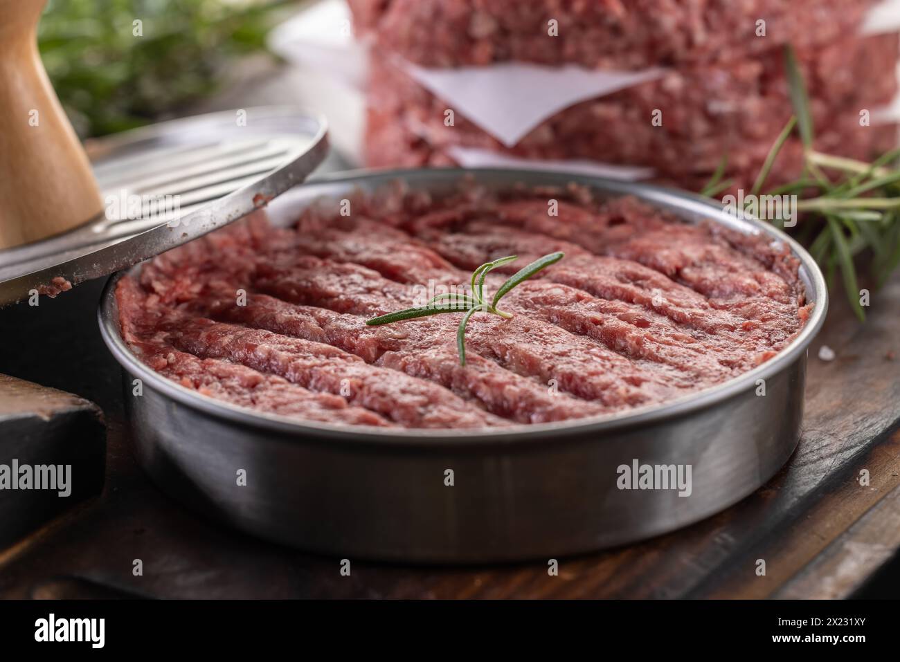 Fresh raw ground beef patties with rosemary salt and pepper made in a ...