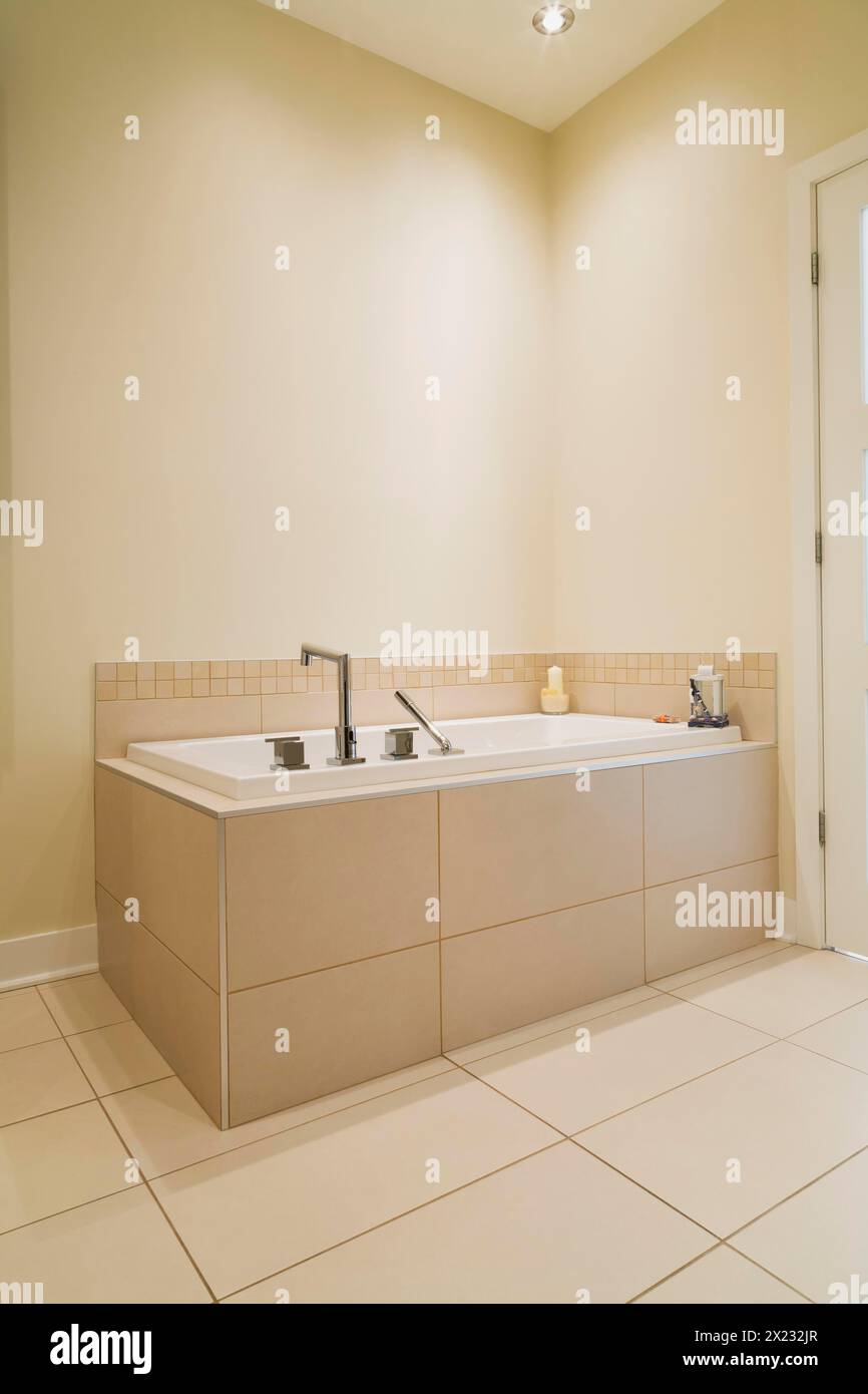 Soaking tub encased in a ceramic tile base in bathroom inside a ...