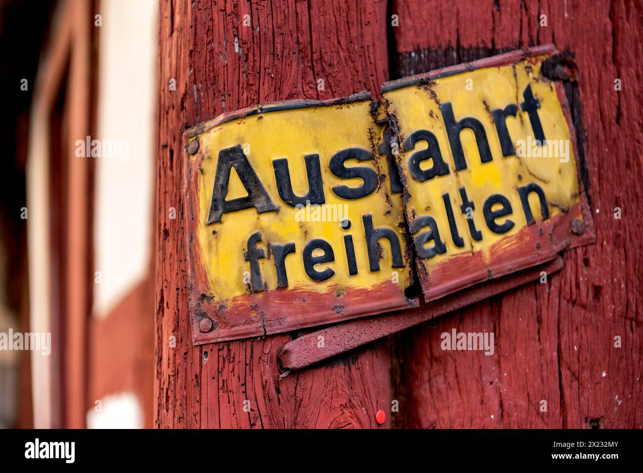 Old sign, keep exit clear, bent and rusty on wooden beam, courtyard ...