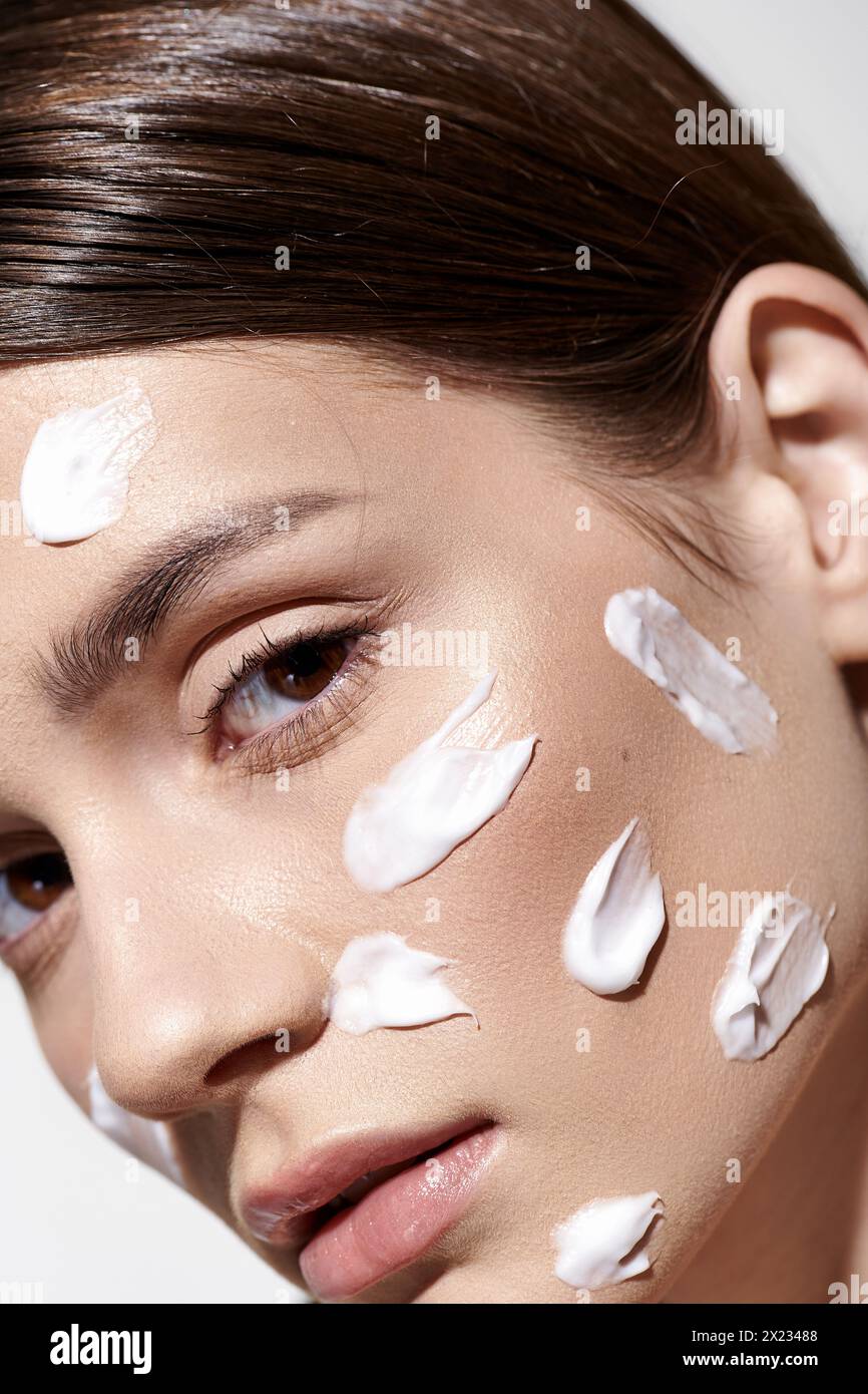 A beautiful young woman with a generous amount of cream on her face ...