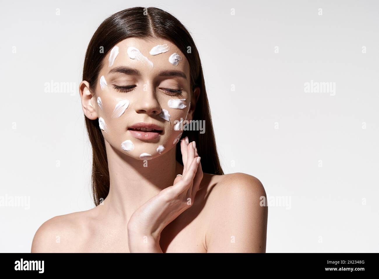 A captivating young woman with delicate white cream adorning her face ...