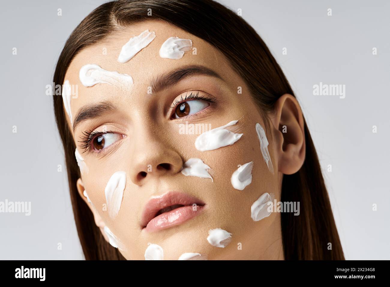 A beautiful young woman with a lot of cream on her face, showcasing her ...