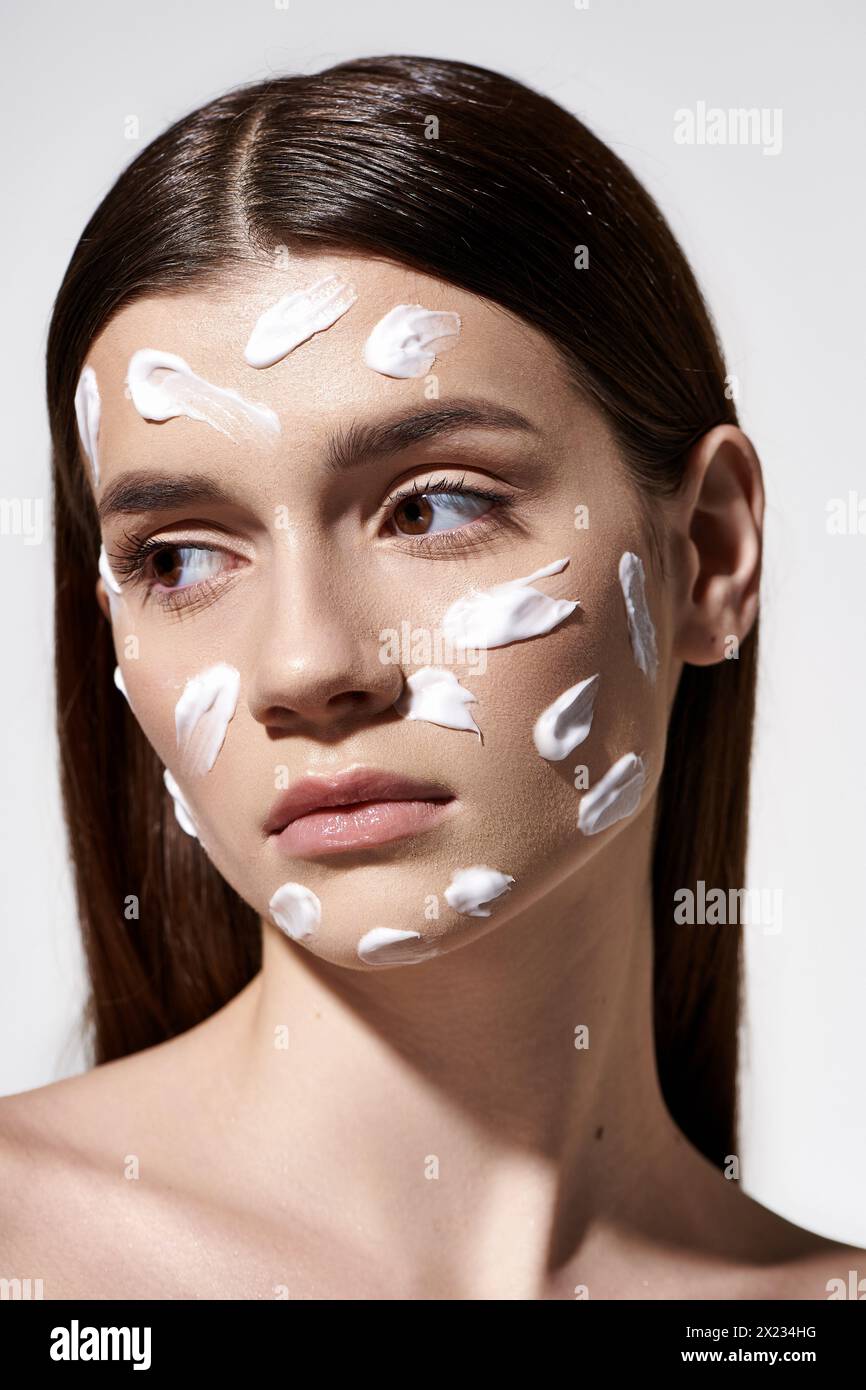 A young woman exudes beauty with a white cream on her face, enhancing ...