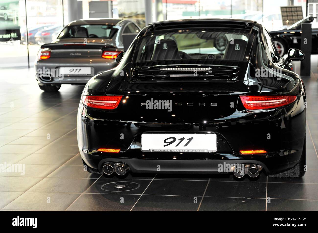 The rear view of a shiny black Porsche 911 in a car dealership ...