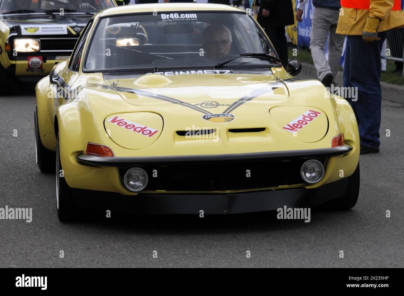 A yellow sports car with racing numbers and sponsor logos during a race ...