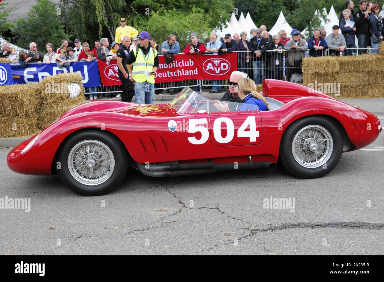 Driver in a red classic racing car with starting number 504 in front of ...