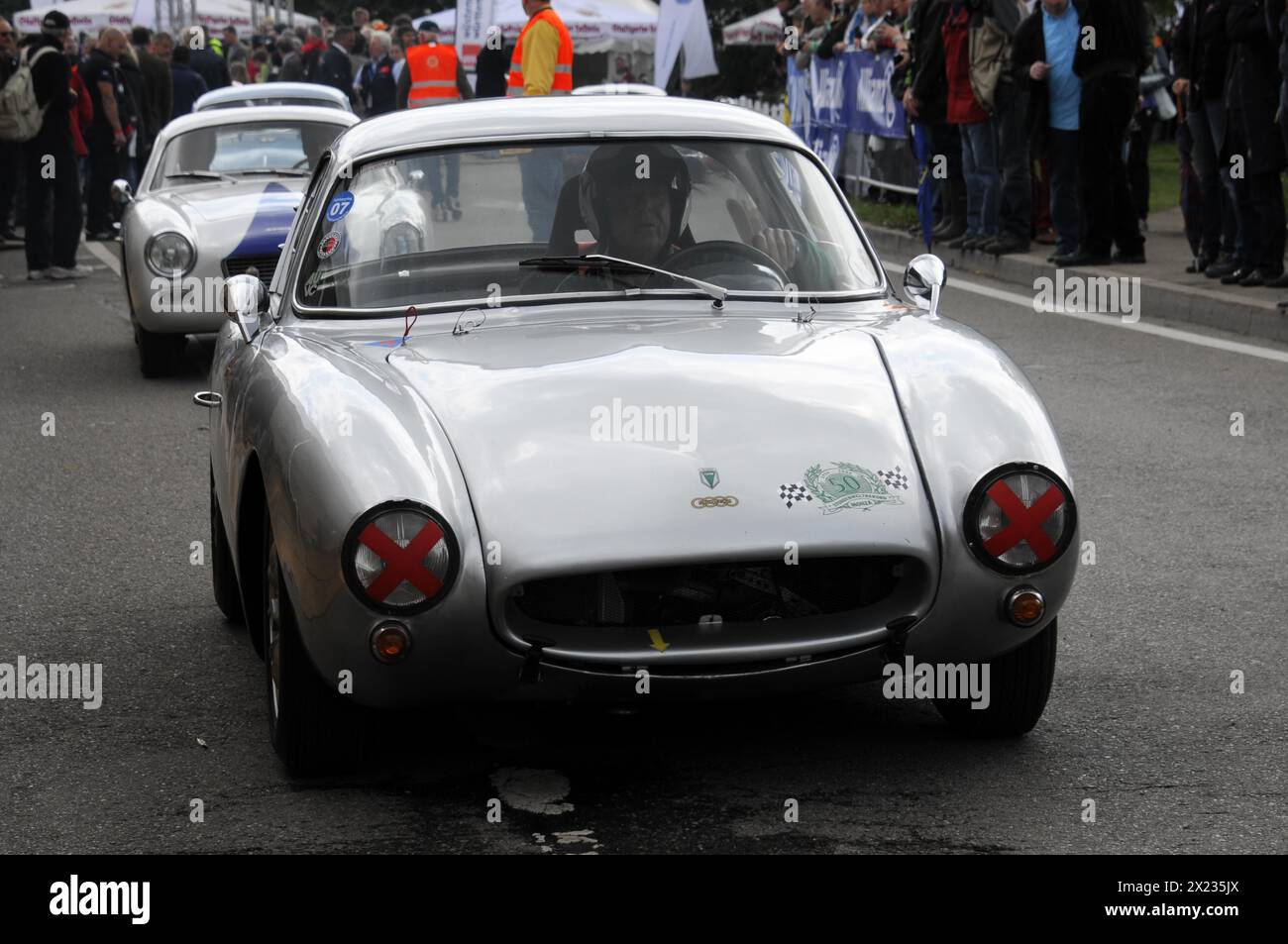 White classic racing car at an event with spectators in the background ...