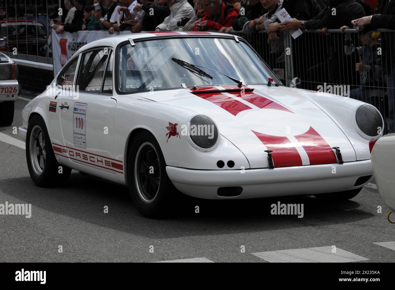 A white Porsche racing car with racing stripes takes part in a car race ...