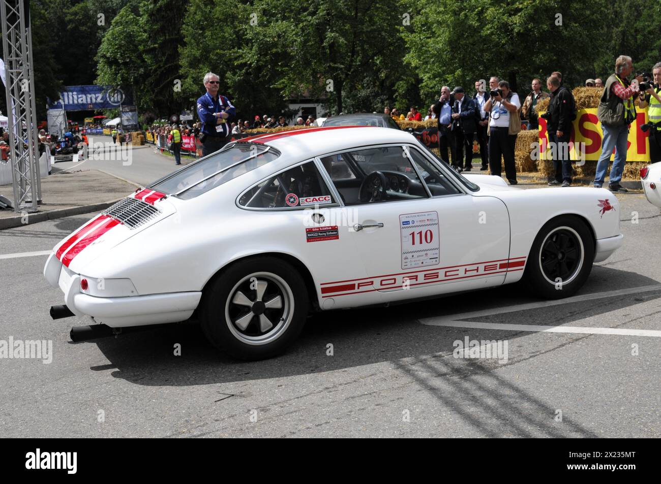 Side view of a white Porsche racing car with racing stripes at a ...