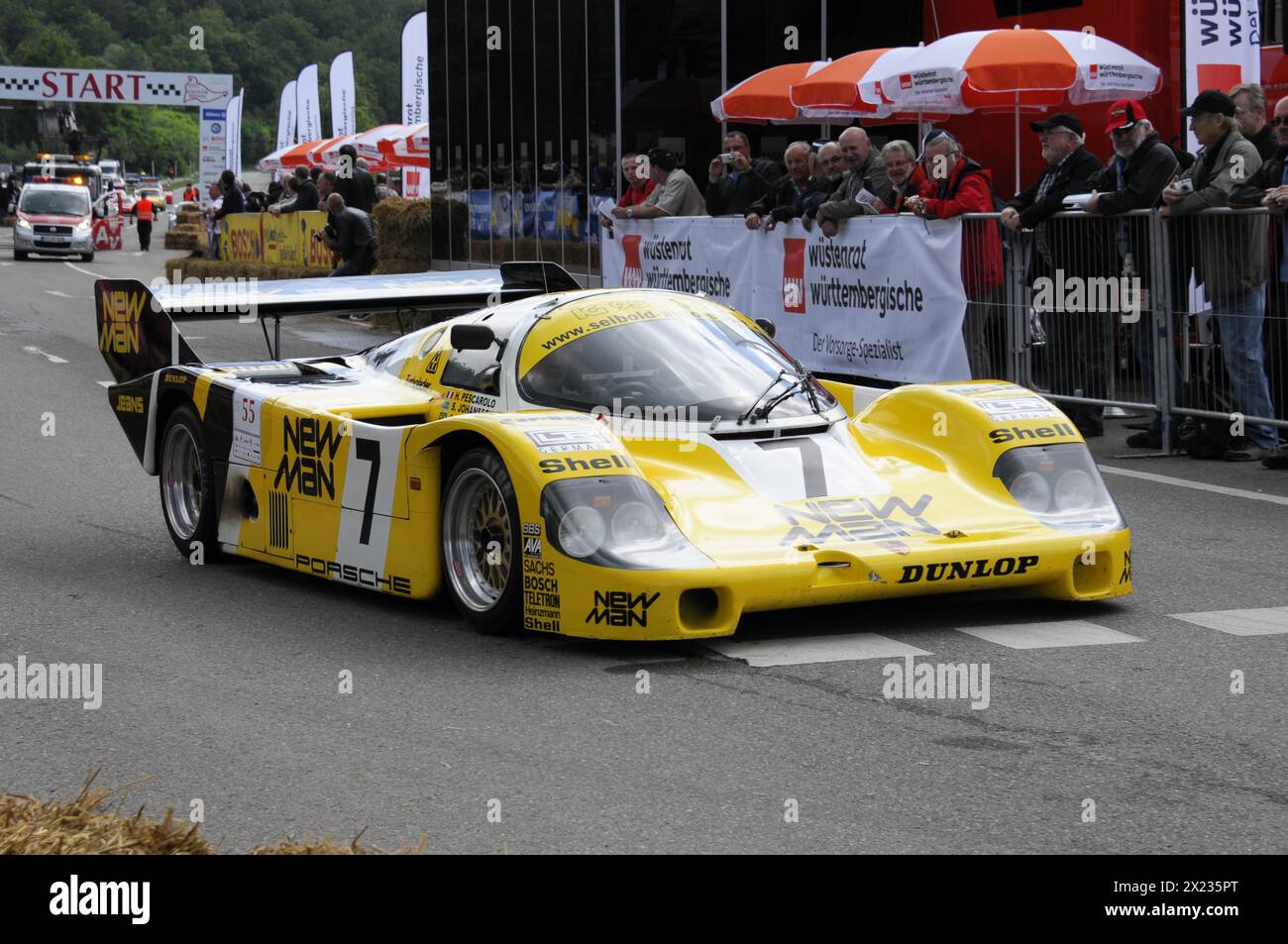 A yellow and black Porsche racing car with NEW MAN branding on a race ...