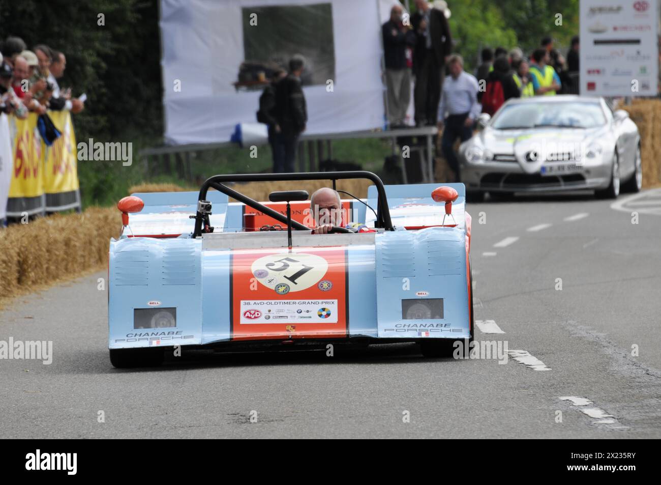 A blue and white open-top racing car with the driver in a helmet on a ...