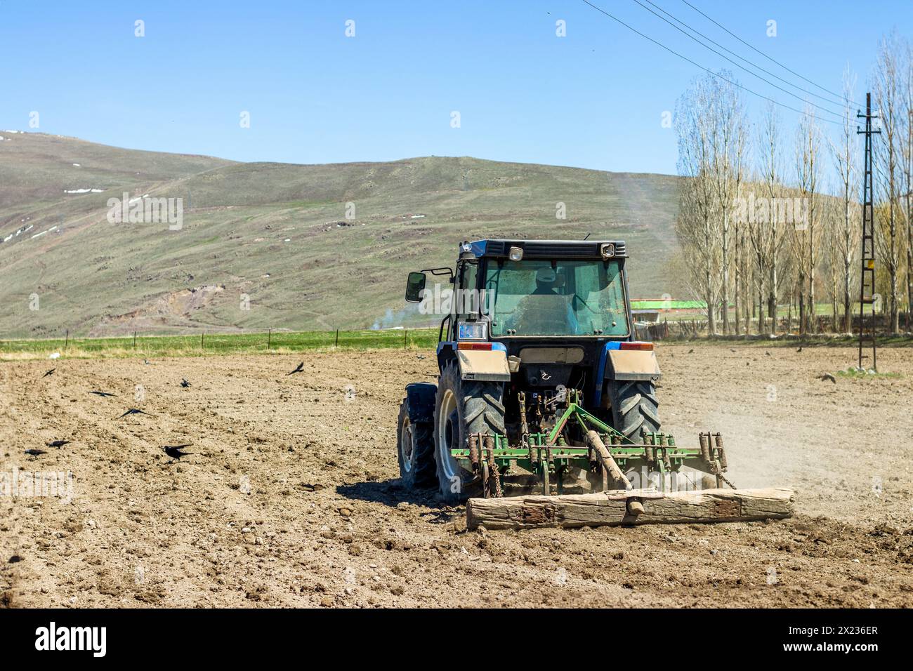 A farmer tilling the soil in spring with a tractor, prepping for a new ...